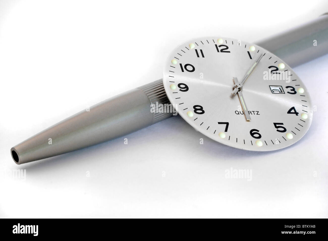 A close up of a clock face resting on an off-focus pen Stock Photo - Alamy