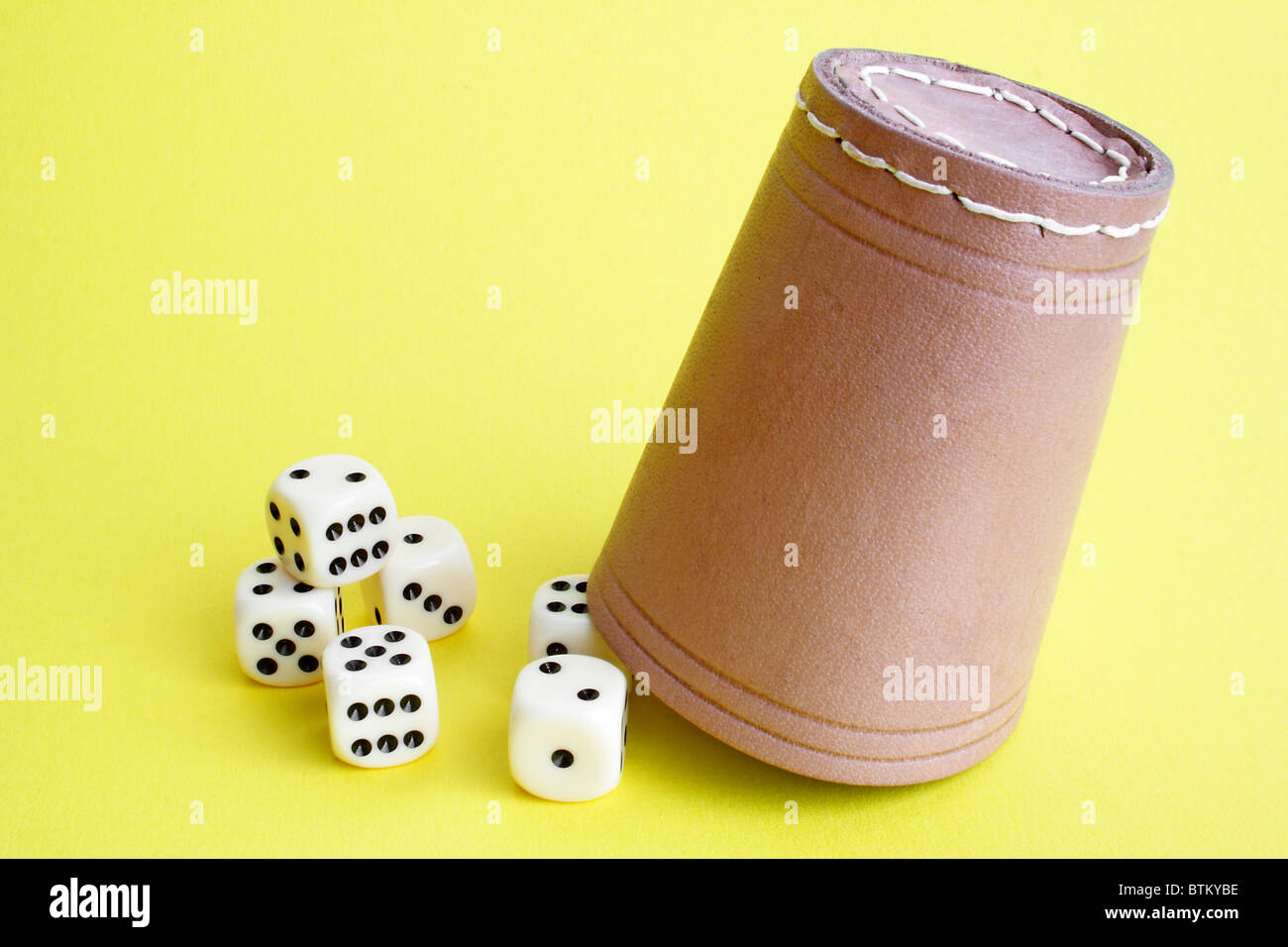 A dice shaker and several dices. All on a plain yellow background Stock ...