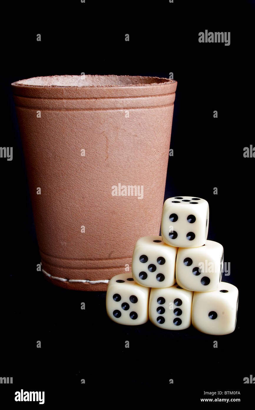 A dice shaker and several dices. All on a plain black background Stock ...