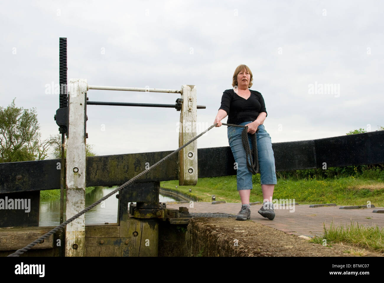 A woman pulling on a rope by a lock at a canal Stock Photo - Alamy