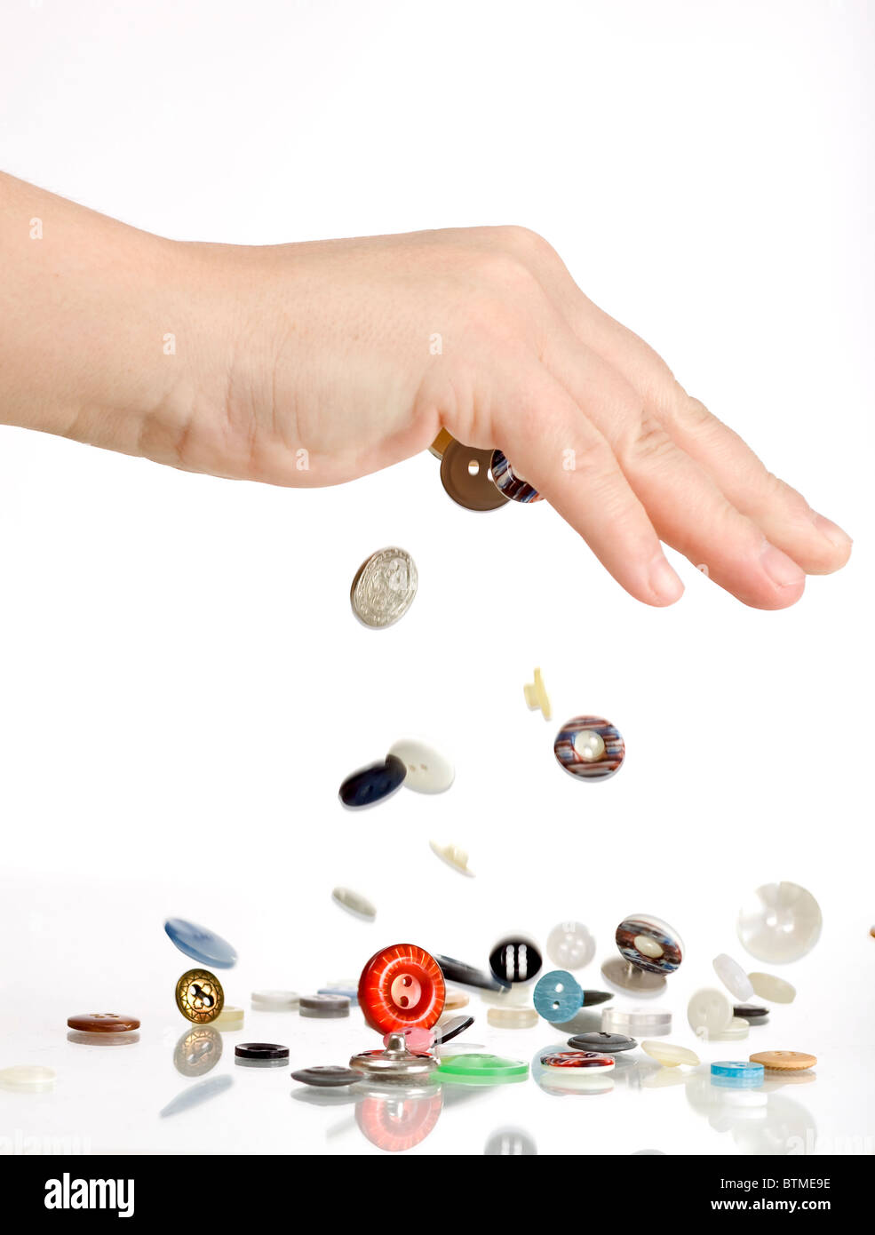 Hand dropping buttons isolated on white background Stock Photo - Alamy