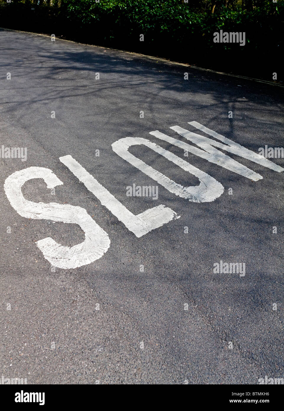 Slow sign painted on black tarmac on a country lane in the UK Stock ...