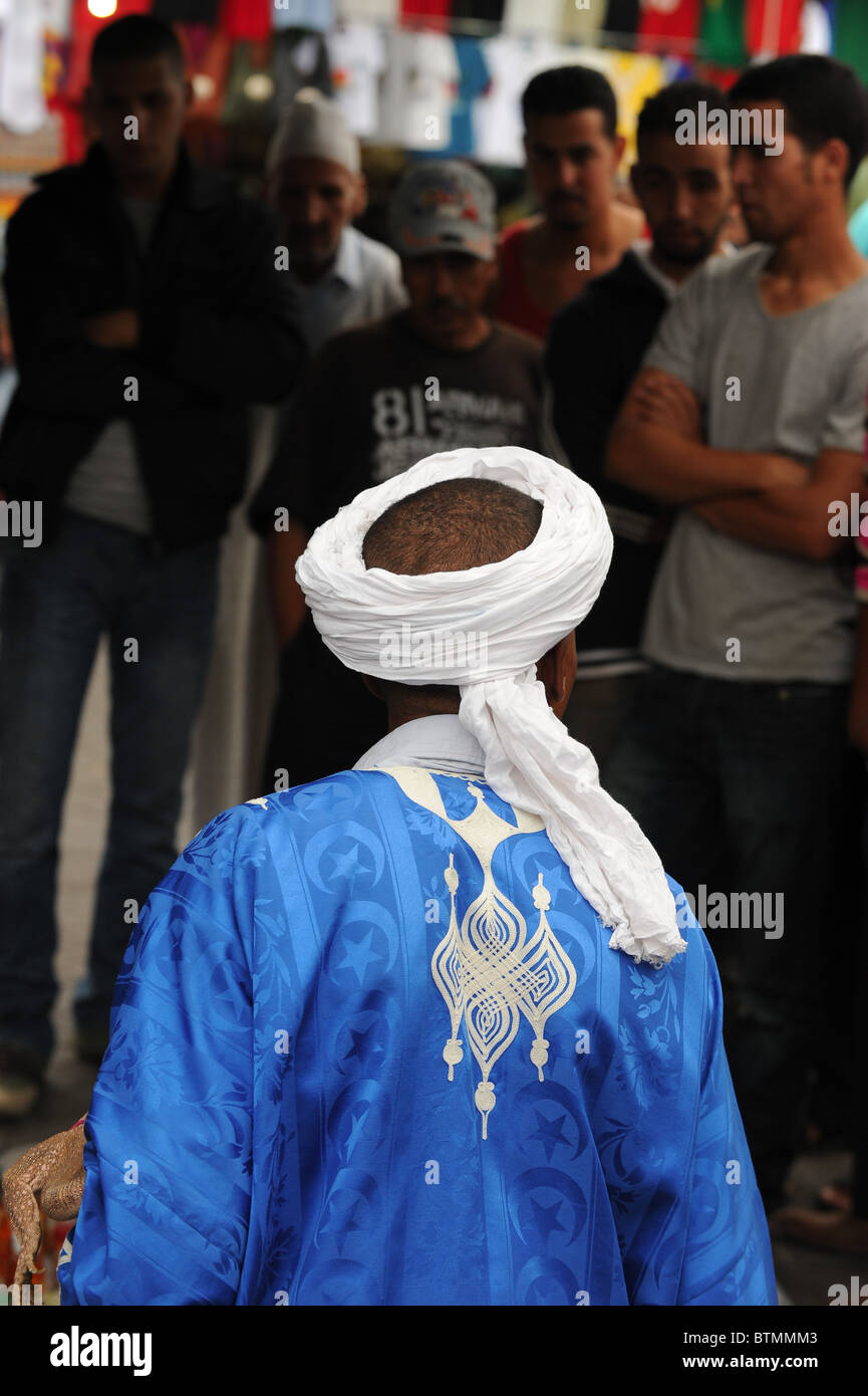 Back view of a turbaned Moroccan trying to sell his herbal remedies to ...