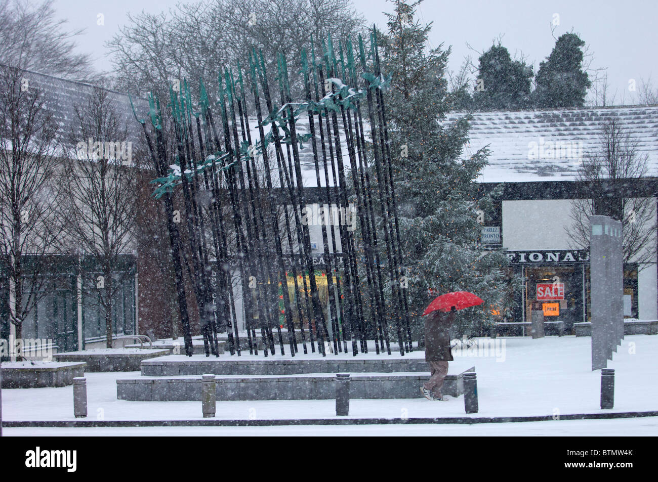A man with a red umbrella walking through a snow shower at Market ...