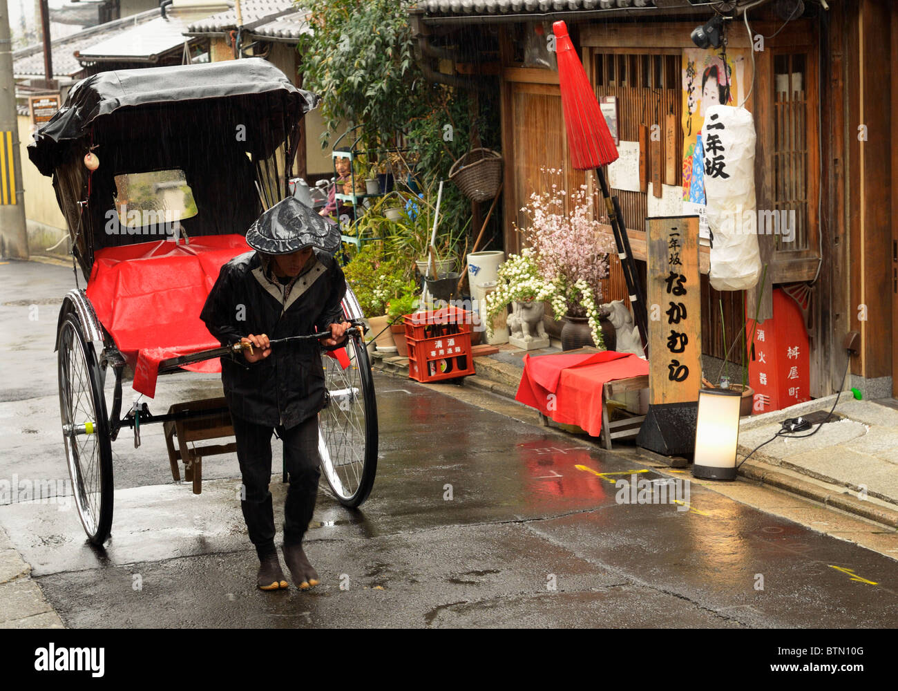 A Japanese Rickshaw pulled under the rain through the old town, Kyoto ...