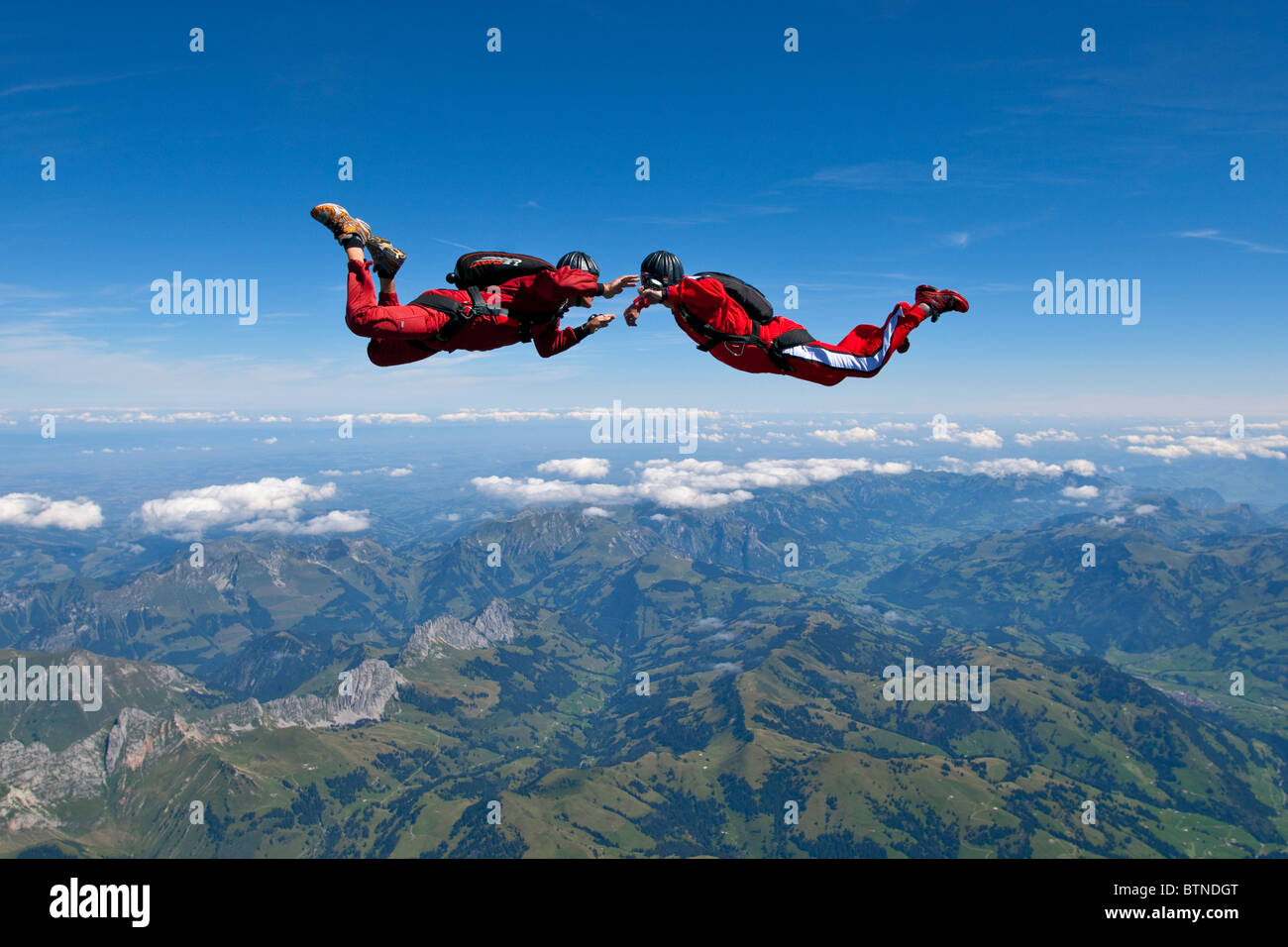 Skydivers are flying close to each other and try go hold hands with ...