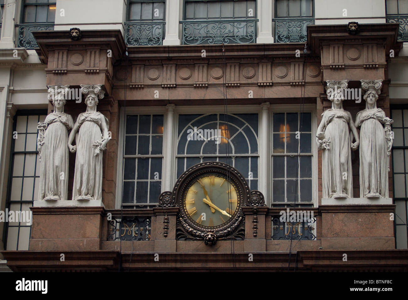 Old style clock on classic architecture with white statues on both side ...