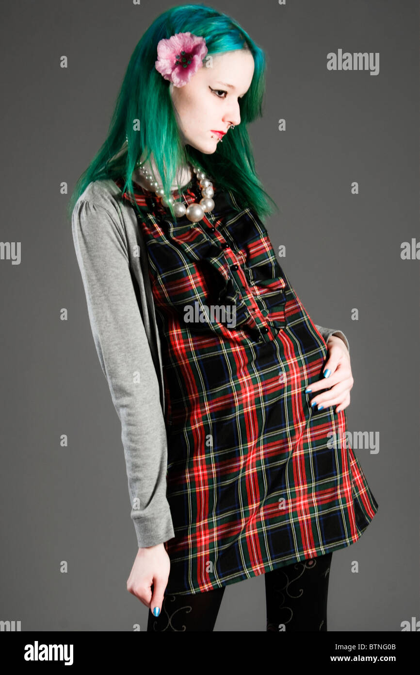A young goth woman with green hair in a plaid dress and cardigan on a ...