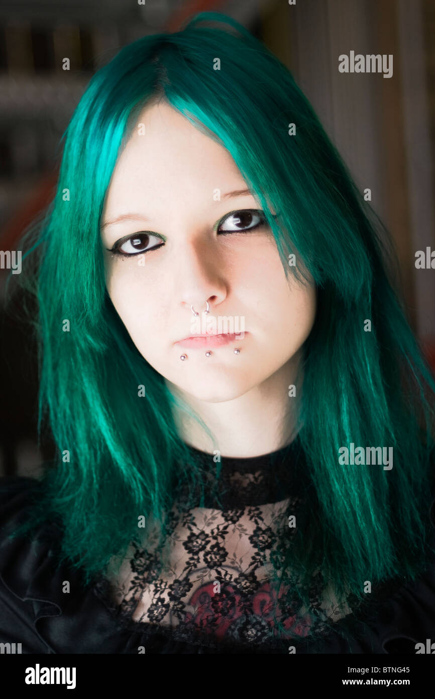 A young goth woman with green hair wearing a green dress and standing ...