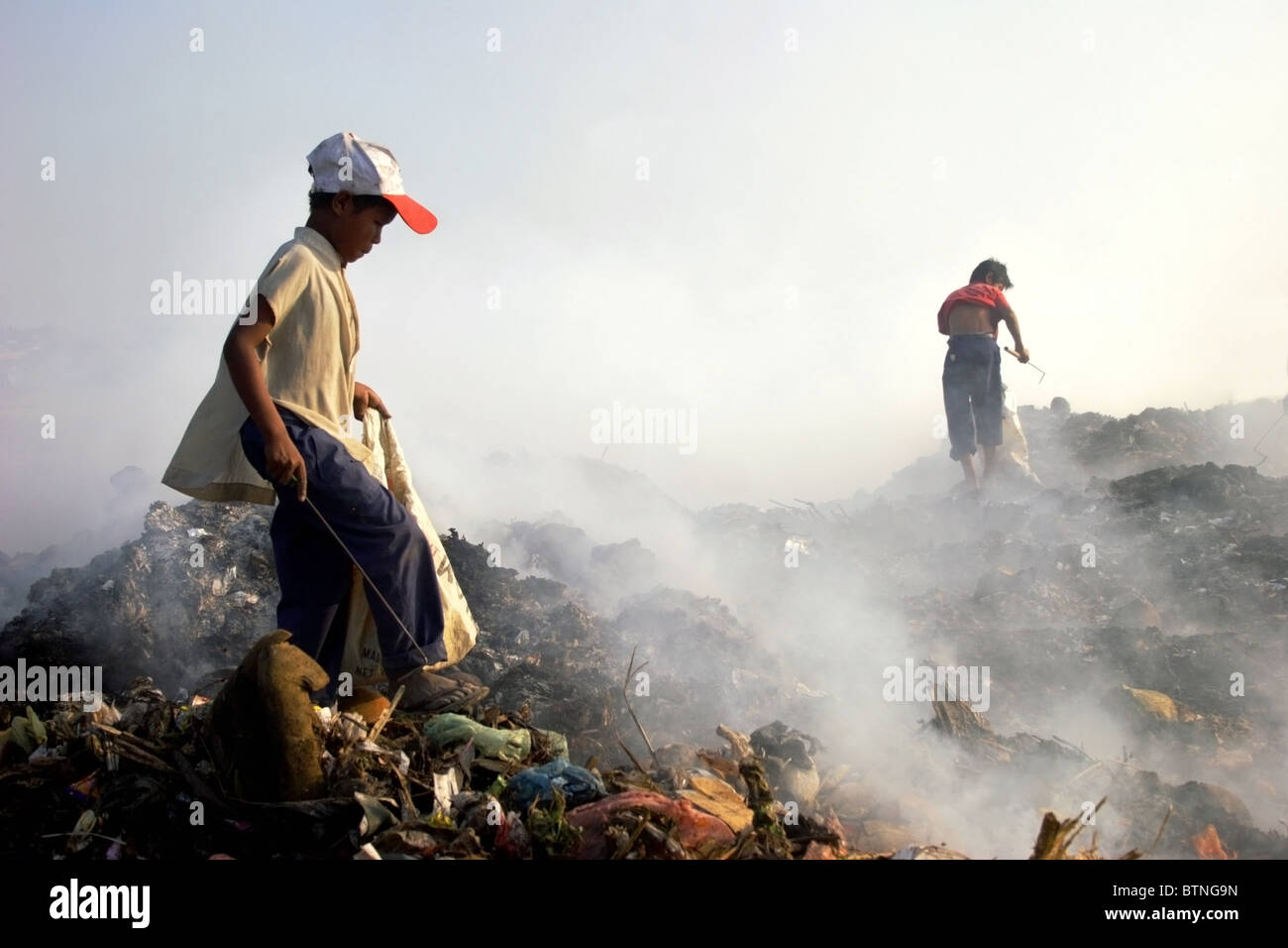 Child laborer boys are searching in burning garbage for scrap metal at ...