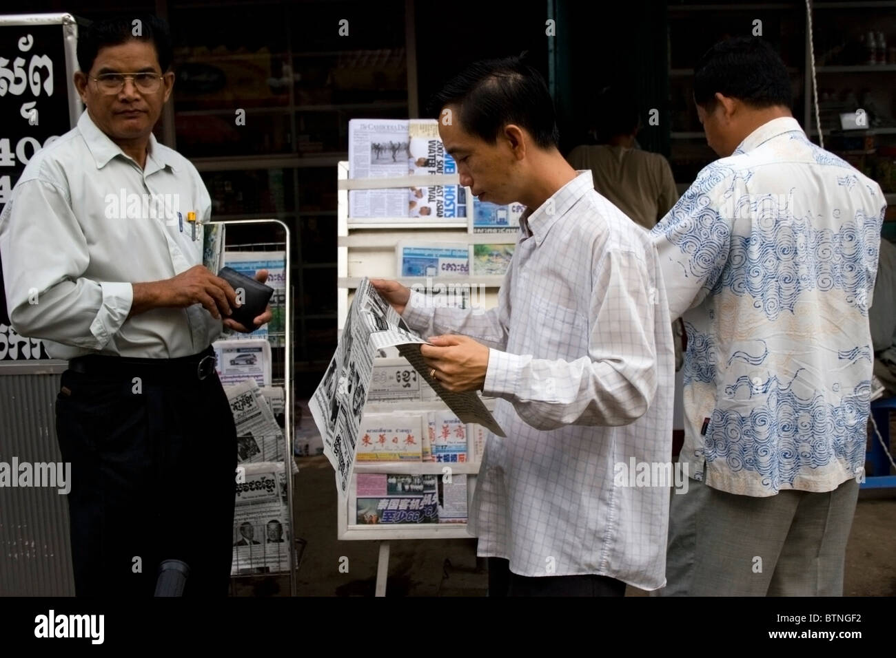 A group of Asian men are reading local Cambodian daily newspapers at a ...