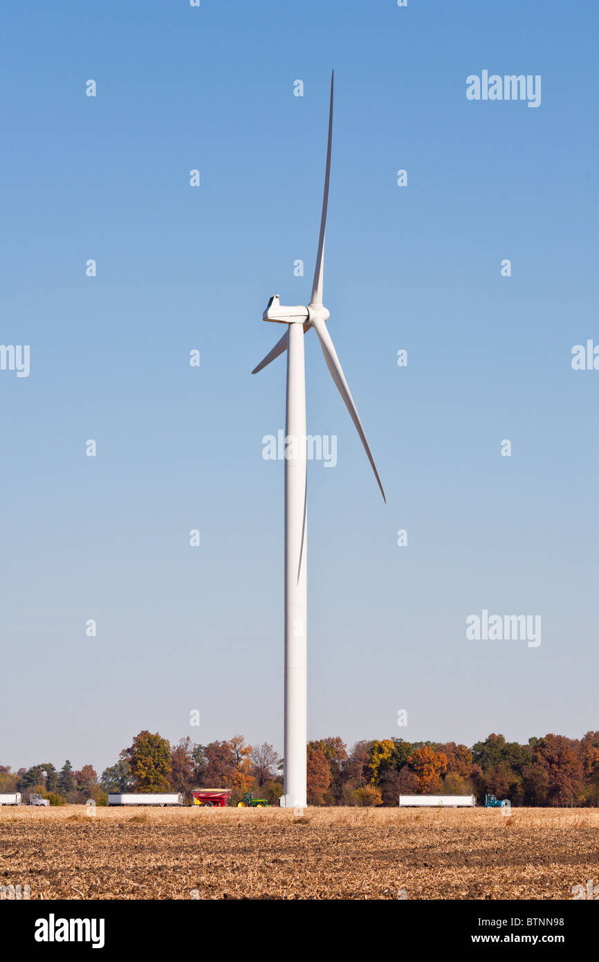 Farmers harvesting corn under wind turbine in corn field near Brookston ...