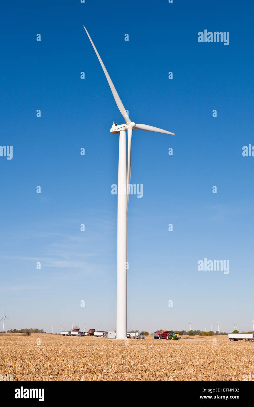 Farmers harvesting corn under wind turbine in corn field near Brookston ...