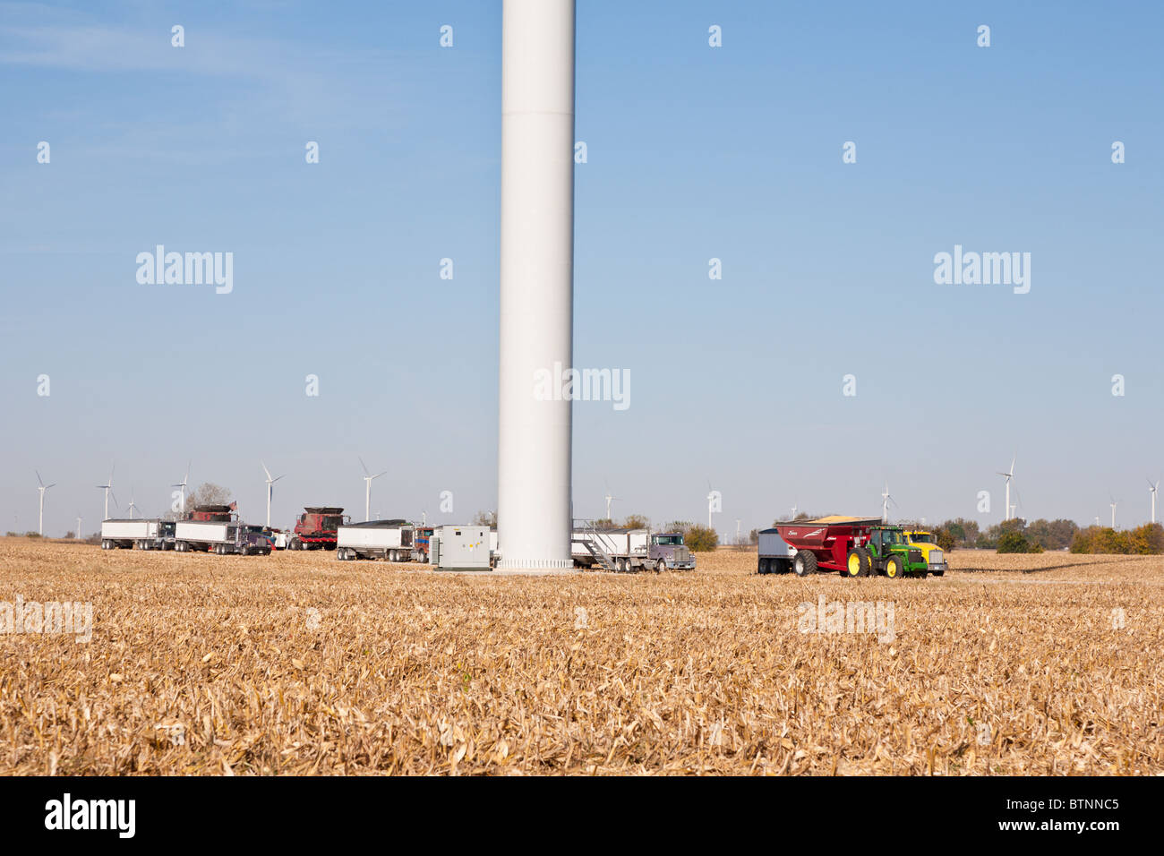 Farmers harvesting corn under wind turbine in corn field near Brookston ...