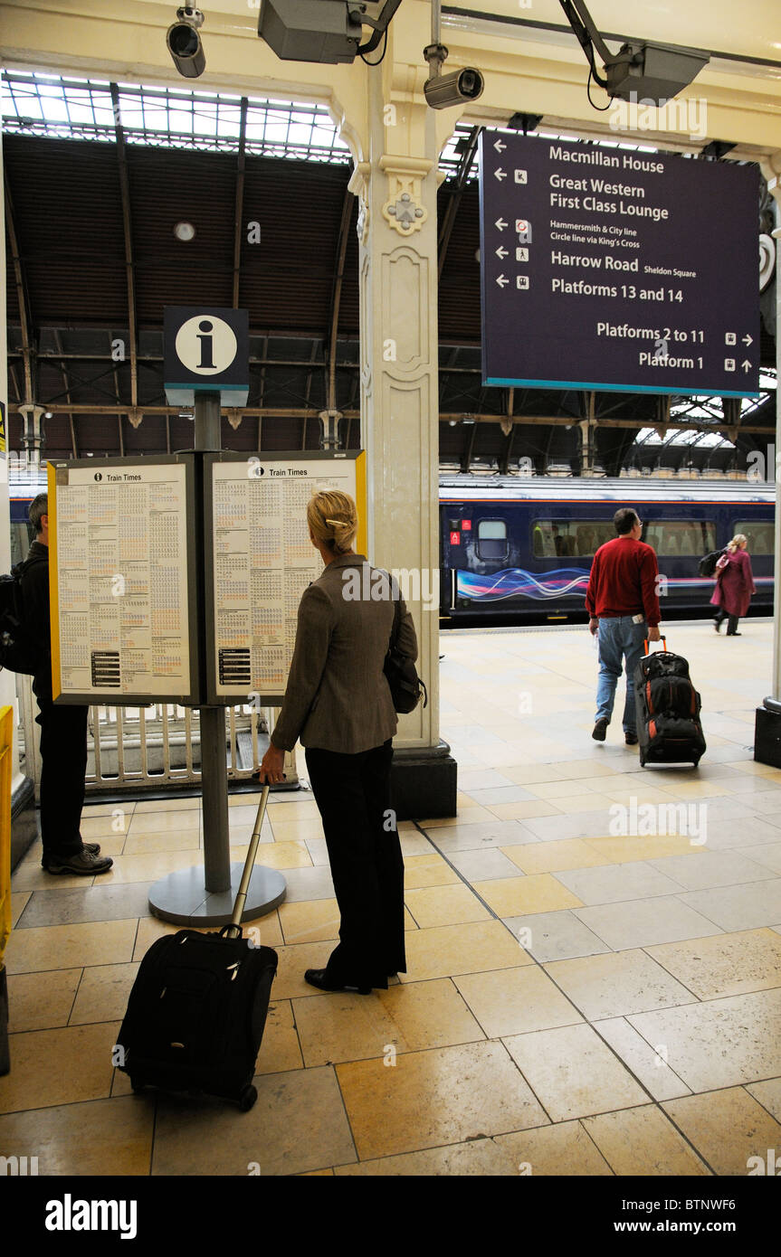 Businesswoman standing on platform viewing train times and information ...