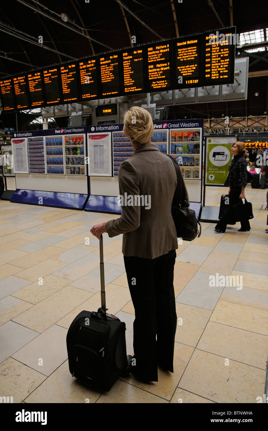 Businesswoman standing on platform viewing train times and information ...