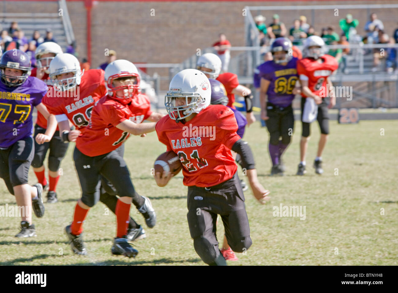 Youth American football game with players running a play and one ...