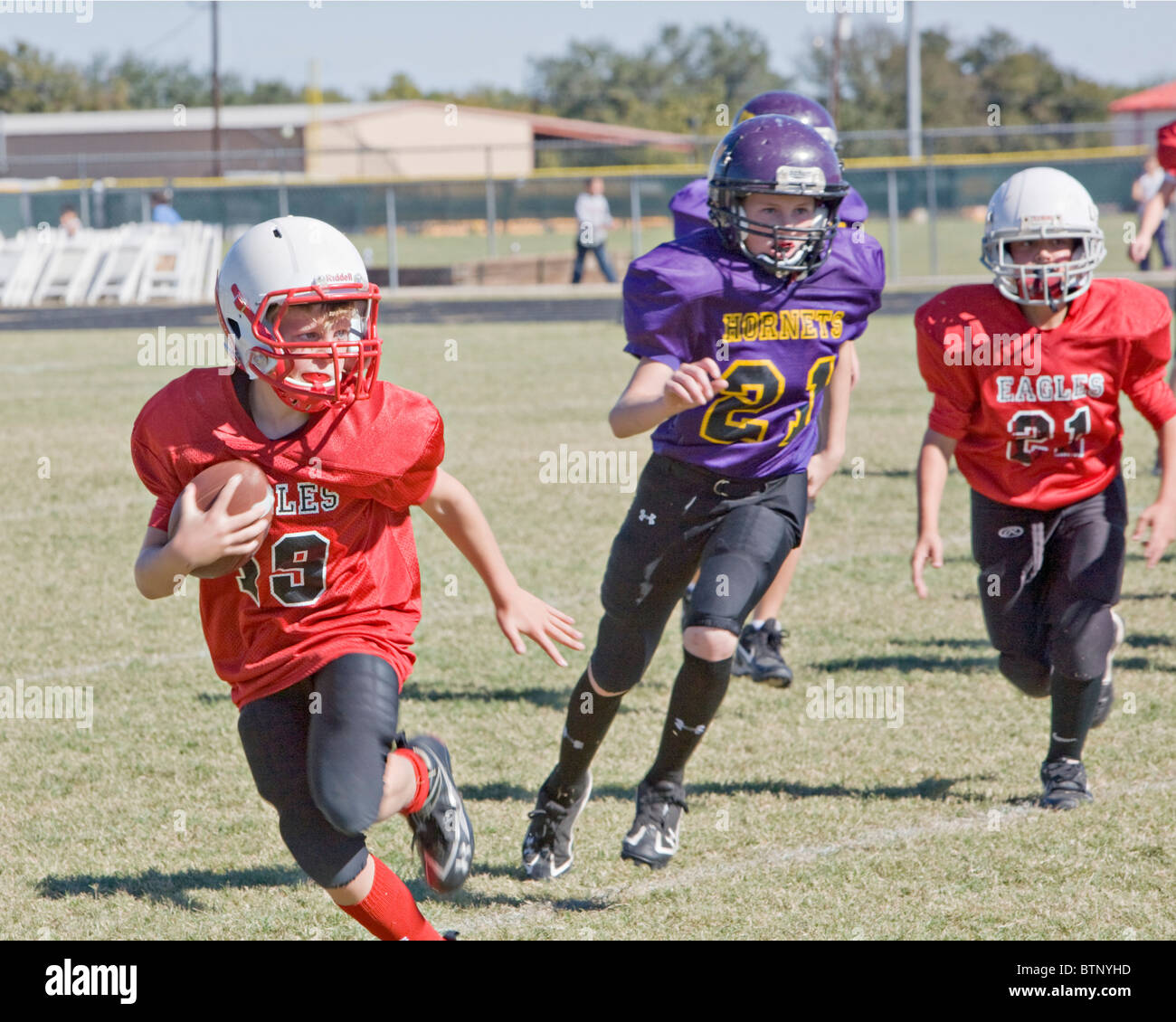 Youth American football players running a play with one carrying ...
