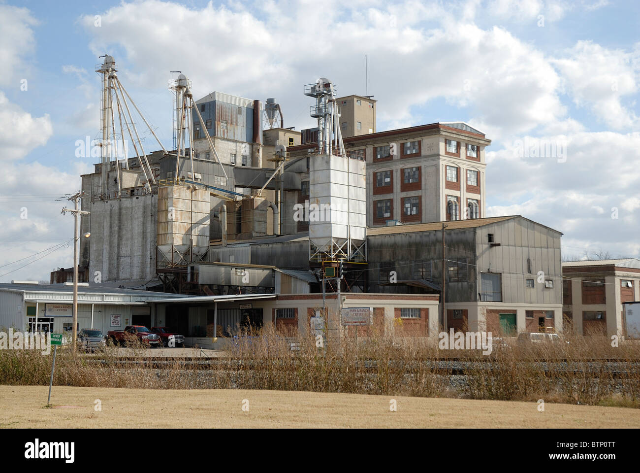 An old large feed mill against a blue sky with clouds Stock Photo - Alamy