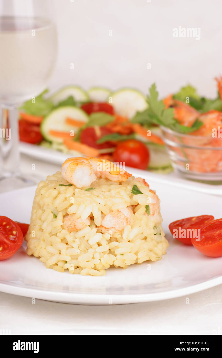 Risotto with shrimps served on a white plate and decorated with cherry ...