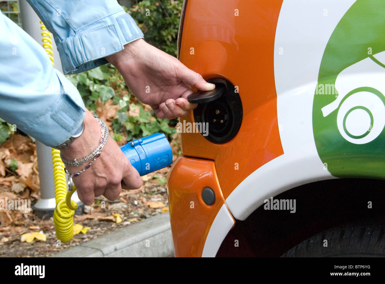 Woman plugging in an electric car rented from GoGo Electric Cars free ...