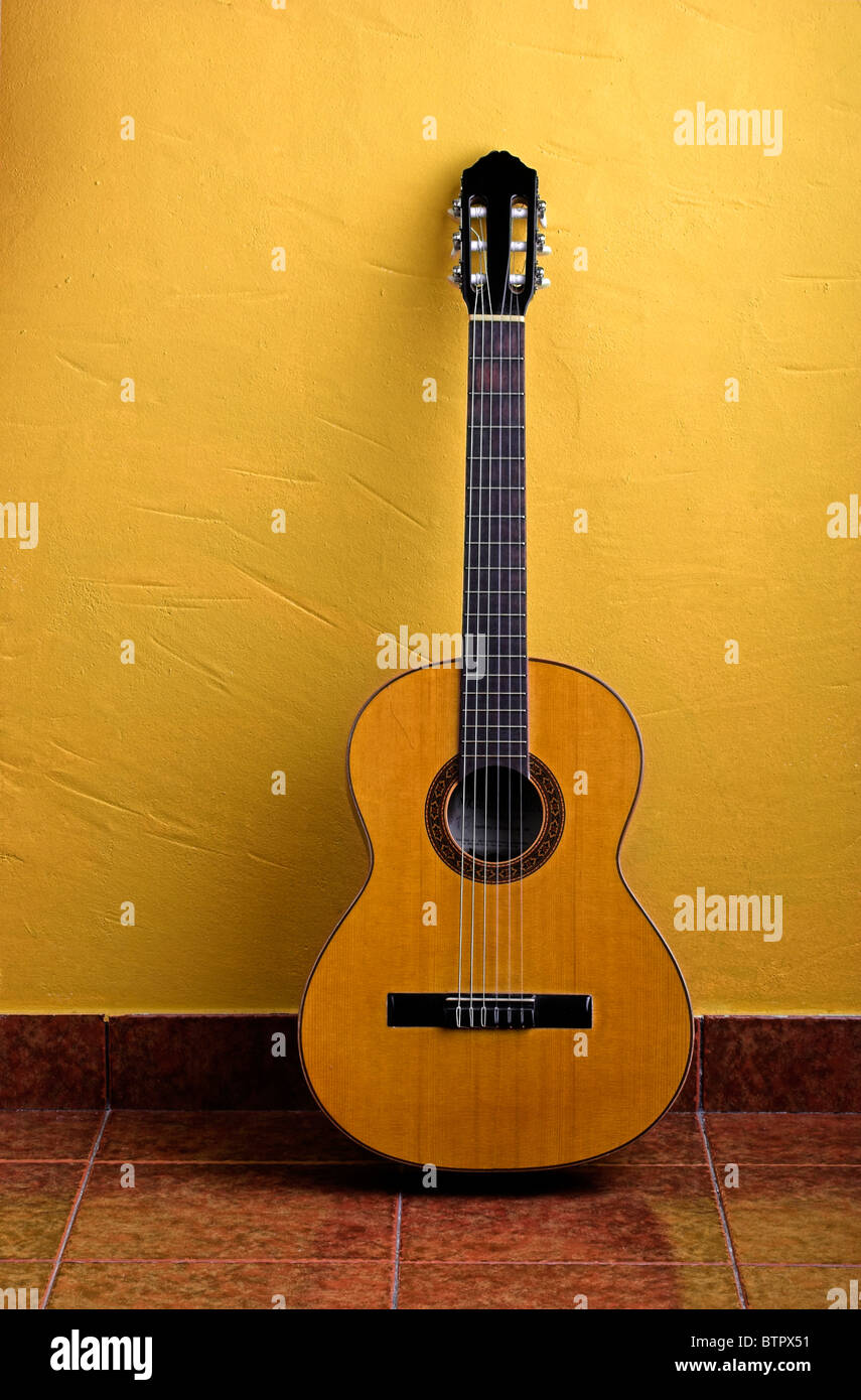 Guitar leaned to a yellow wall Stock Photo - Alamy