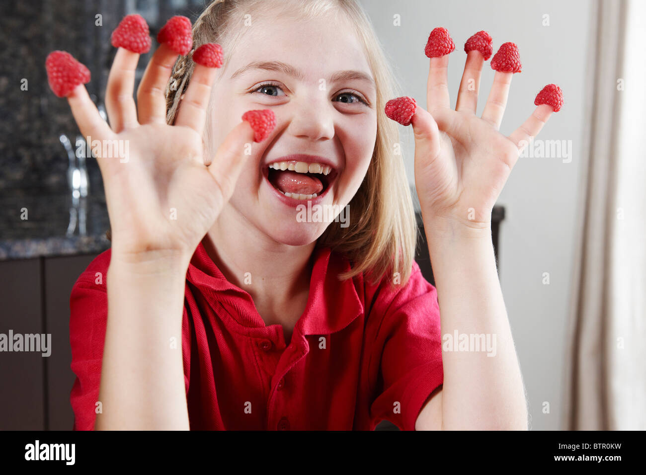 Girl with raspberries on fingers Stock Photo - Alamy