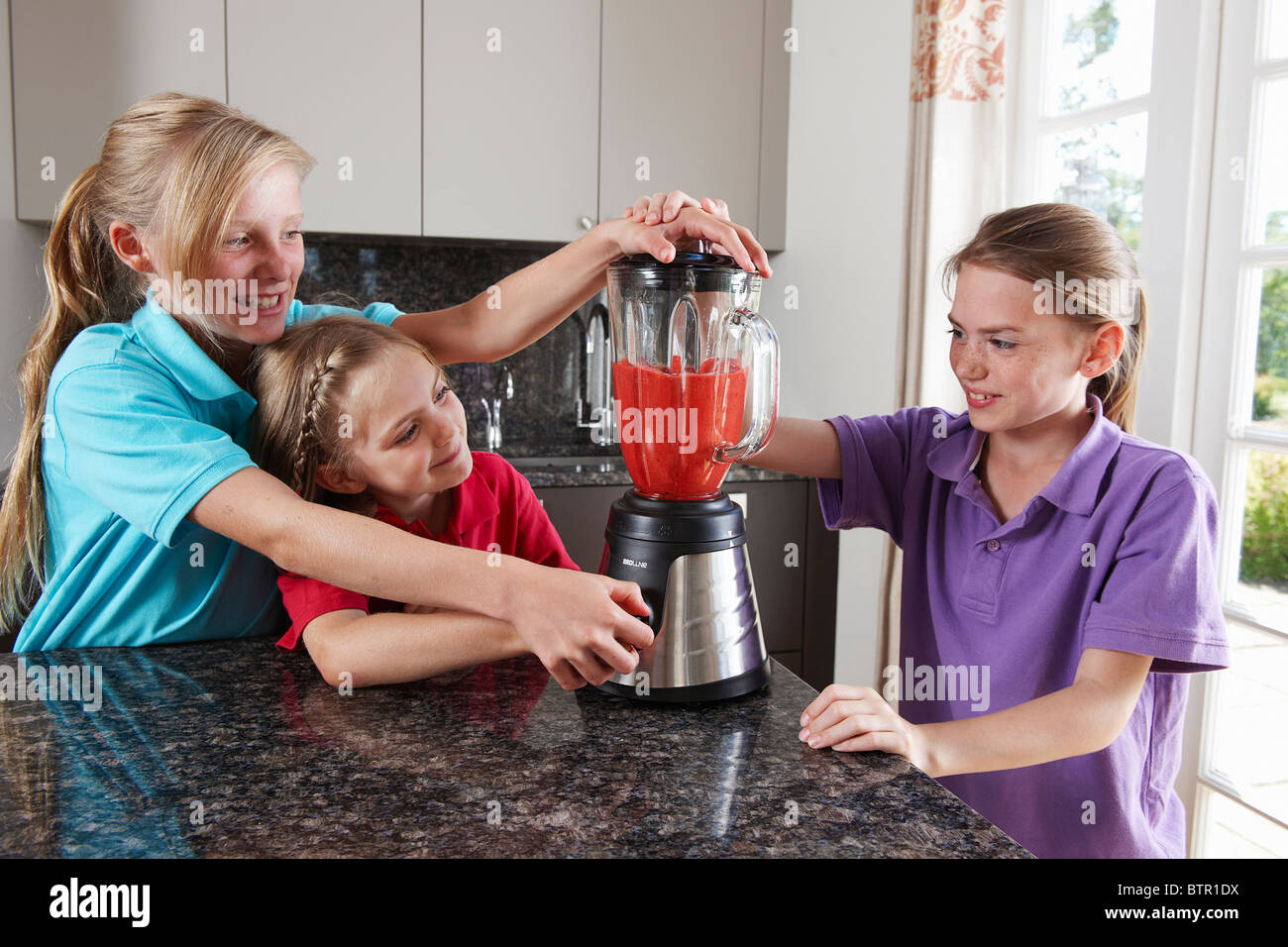 Girls mixing fruit in blender Stock Photo - Alamy