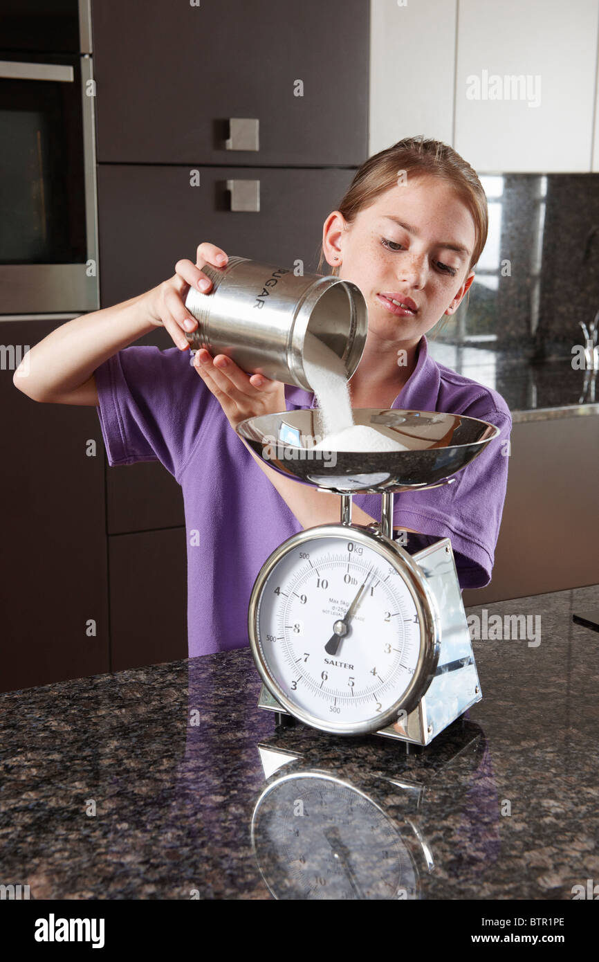 Girl weighing sugar on kitchen scales Stock Photo - Alamy