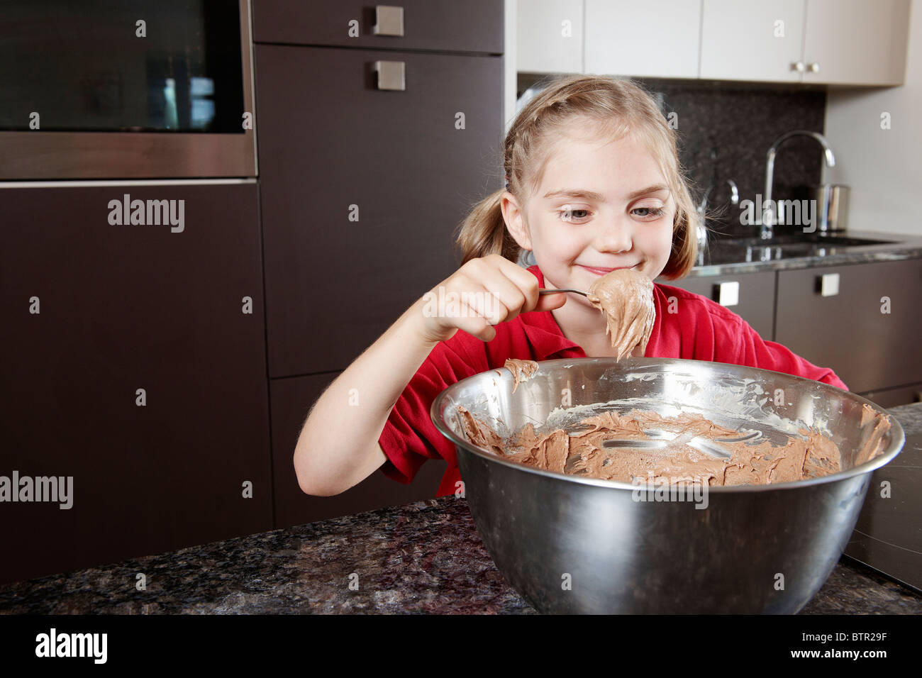 Girl eating cake mix from the bowl Stock Photo - Alamy