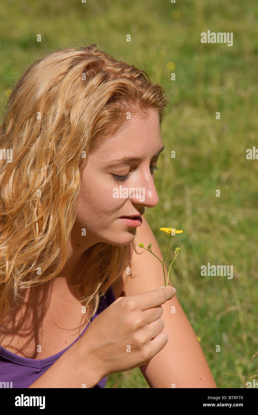 Young pretty woman smelling a yellow alpine wildflower Stock Photo - Alamy