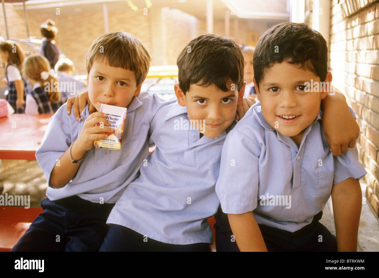 boys eat lunch on Catholic schoolyard friend touch hug smile happy ...