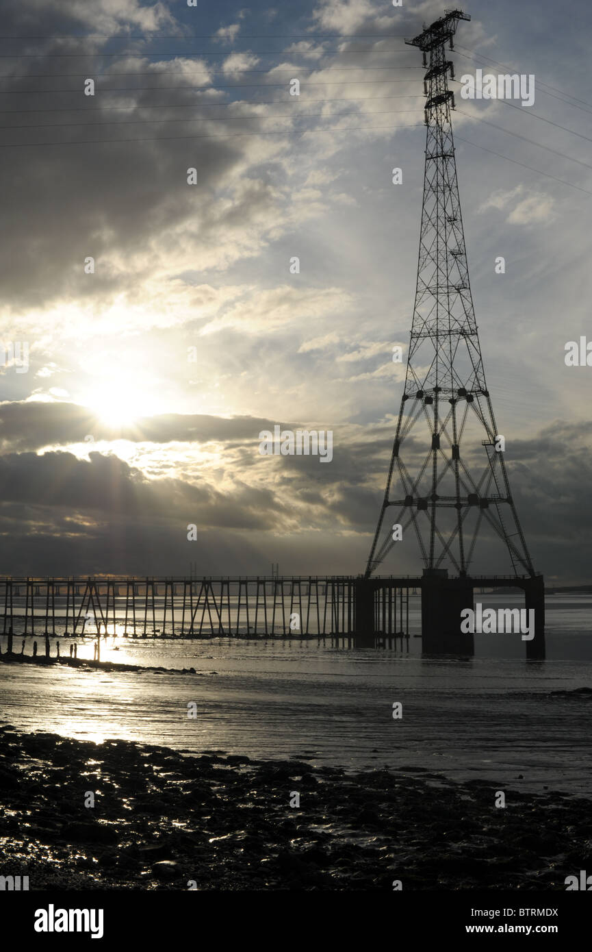 Electricity pylon and pier in the River Severn with a setting sun ...