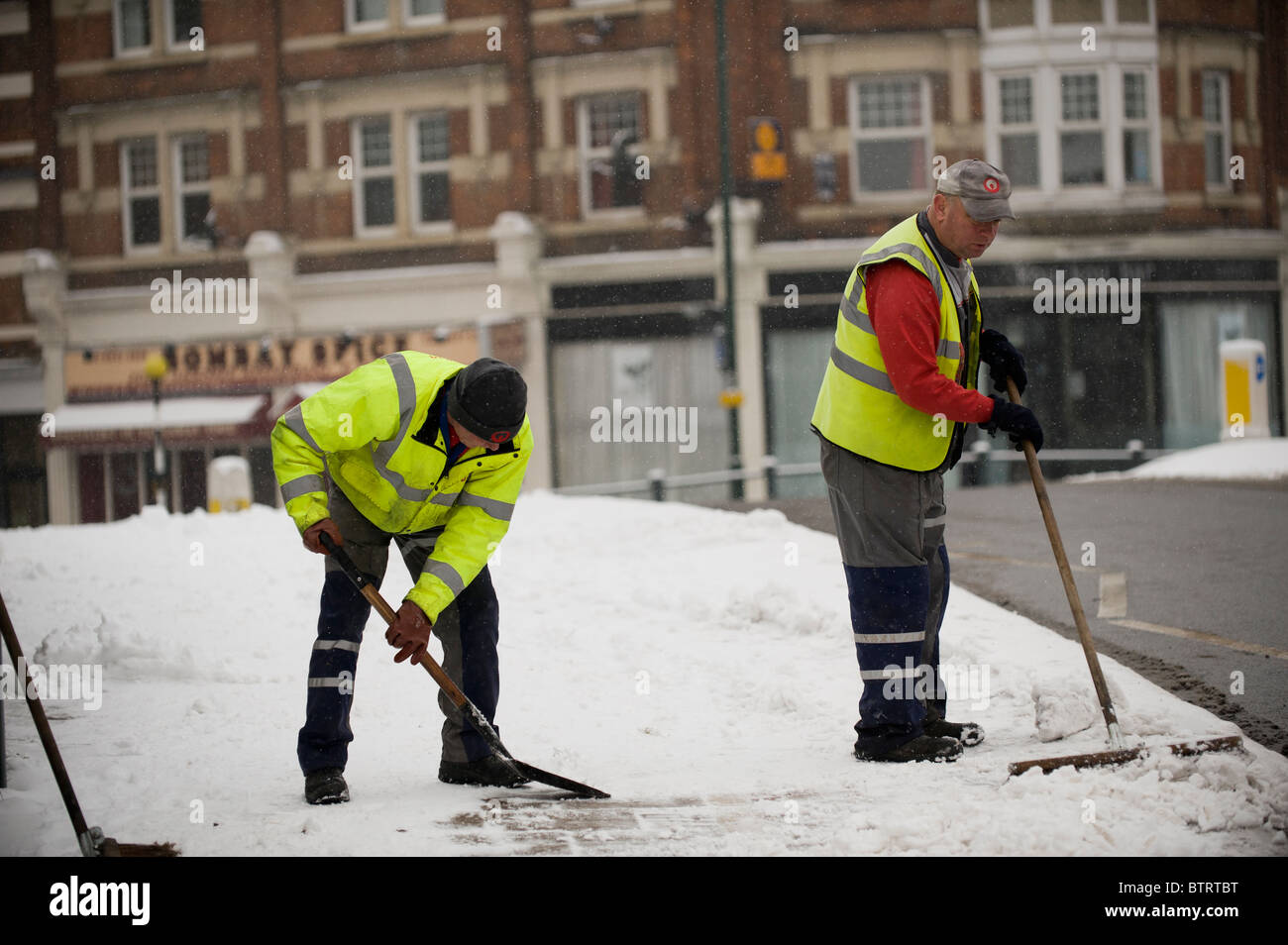 Local authority workers clear snow and ice off the pavement Stock Photo ...