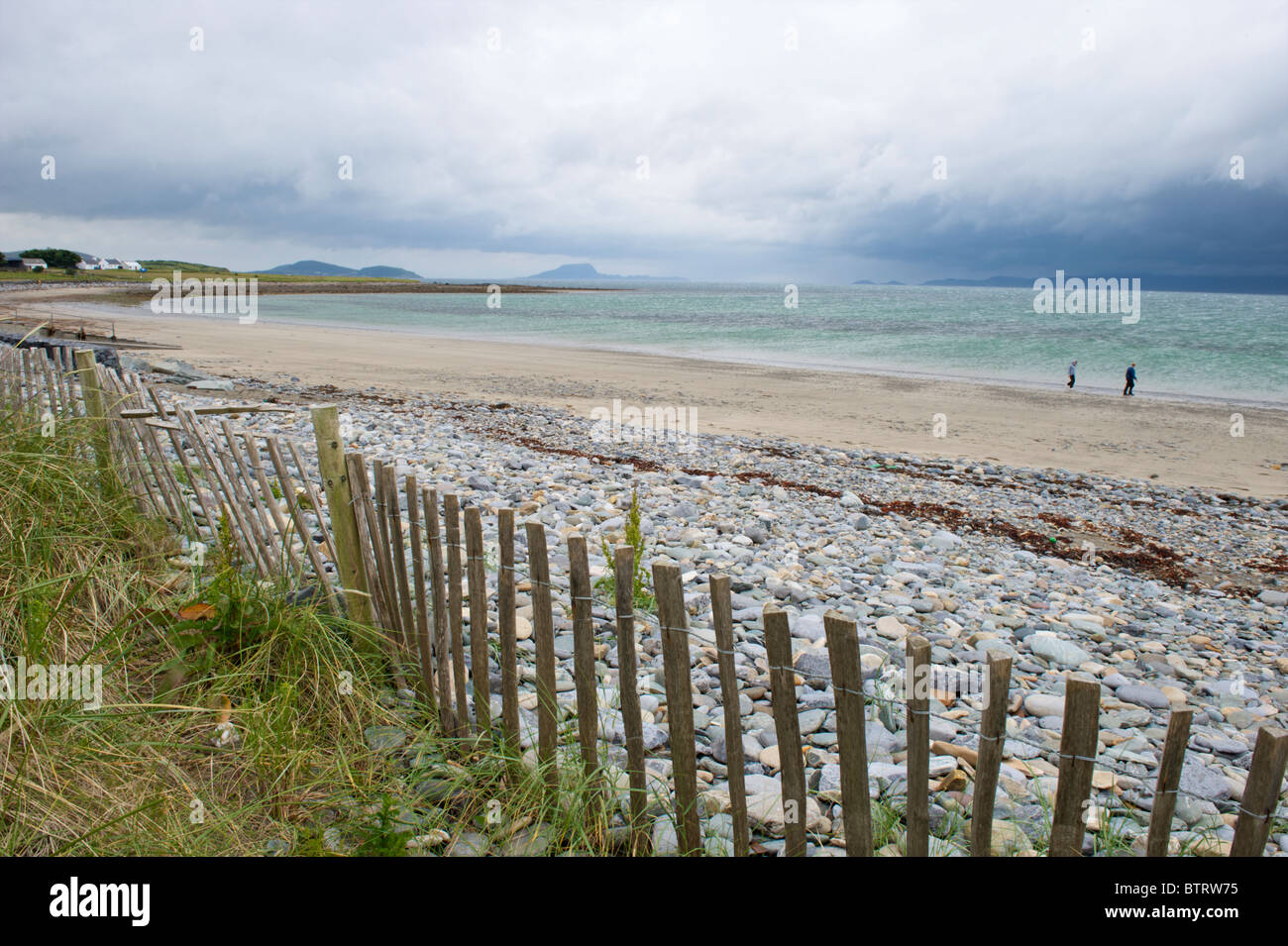 Storm clouds over walkers on Bertra beach with a view of Clare Island ...