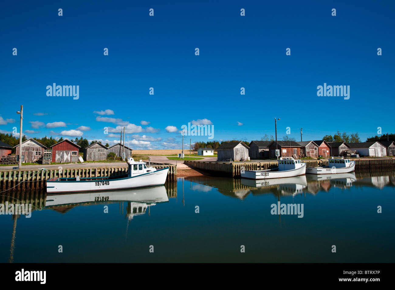 Boats are reflected in the smooth water of Launching Harbour in PEI ...
