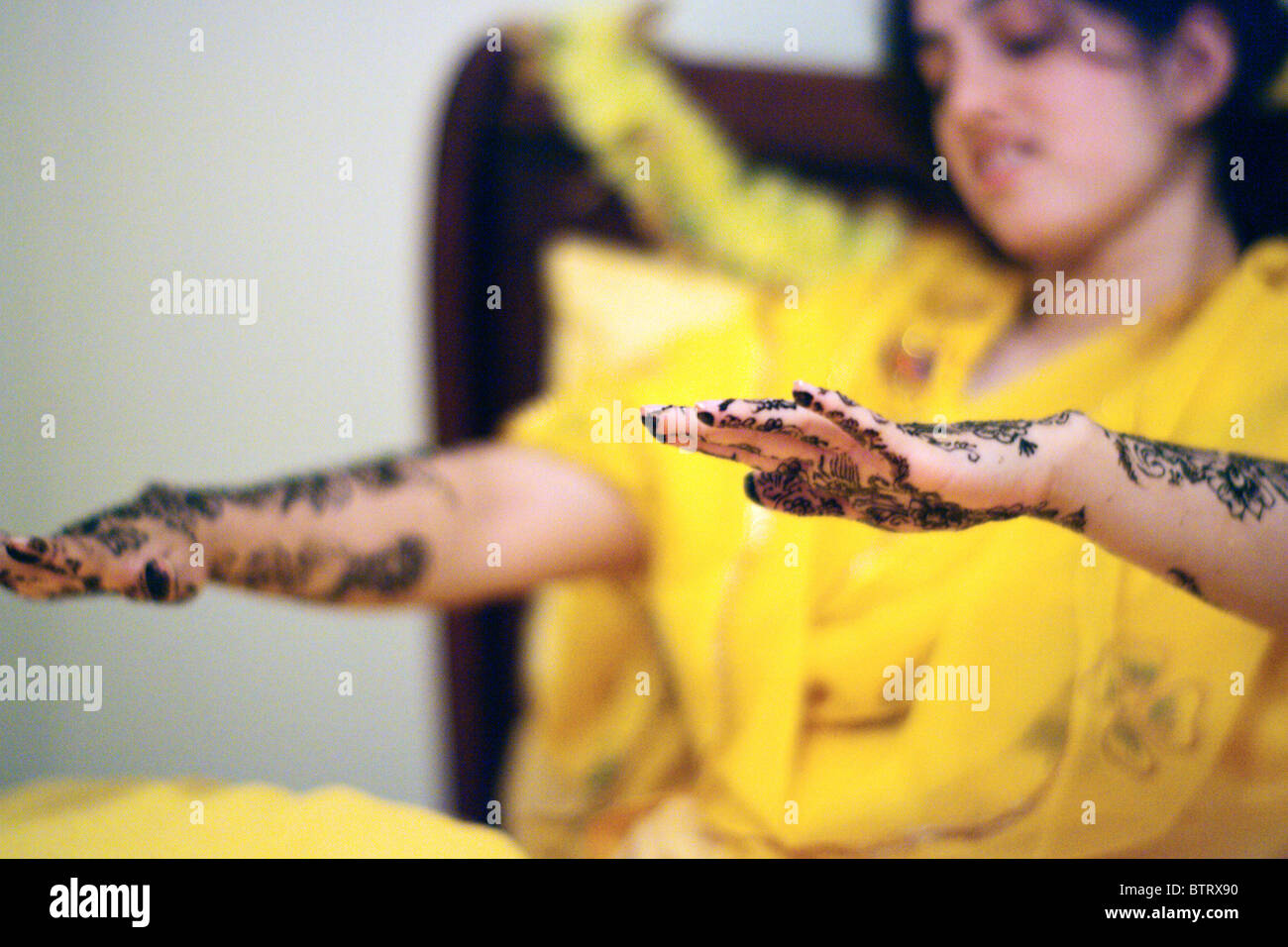 Young Muslim bride-to-be admires the elaborate henna designs painted on ...