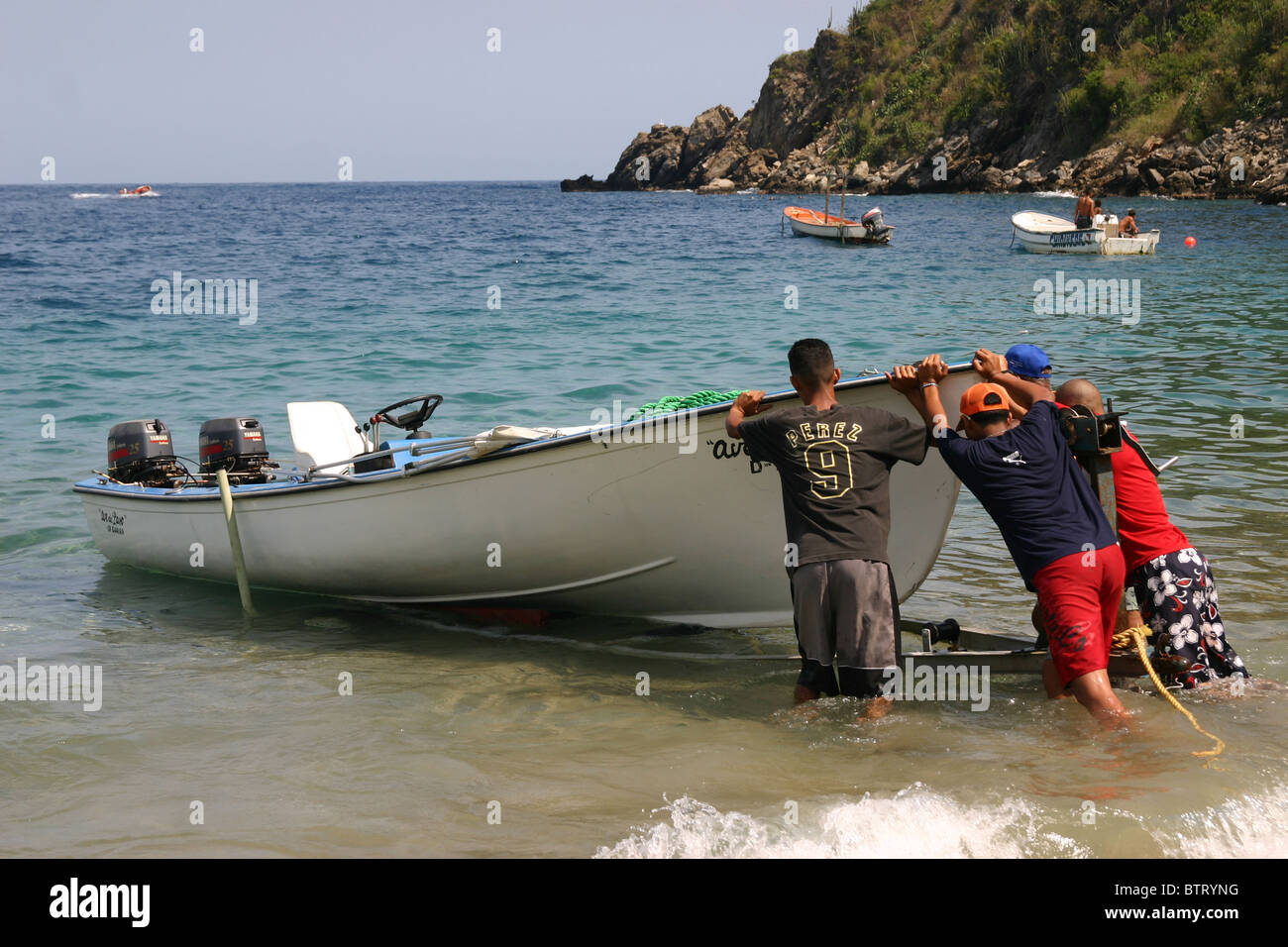 Fishermen pushing a boat out in the Caribbean sea, off the coast of ...