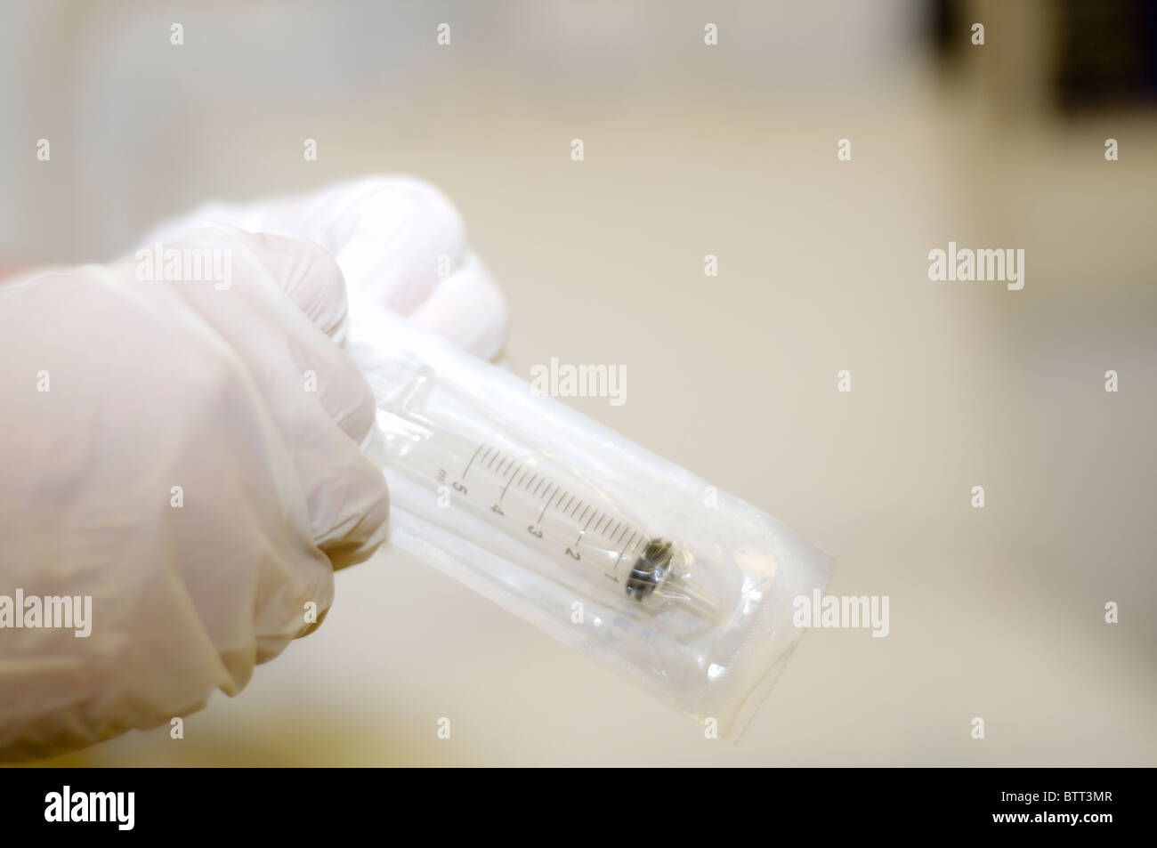 Close up of a nurse or doctor taking a syringe out of a sterile packet ...