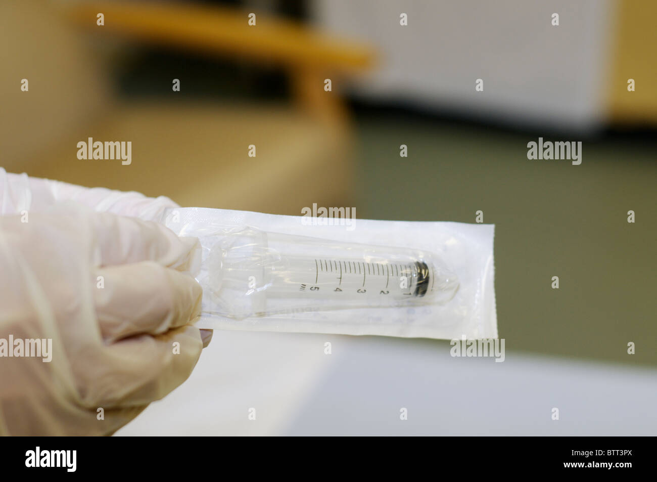 Close up of a nurse or doctor taking a syringe out of a sterile packet ...
