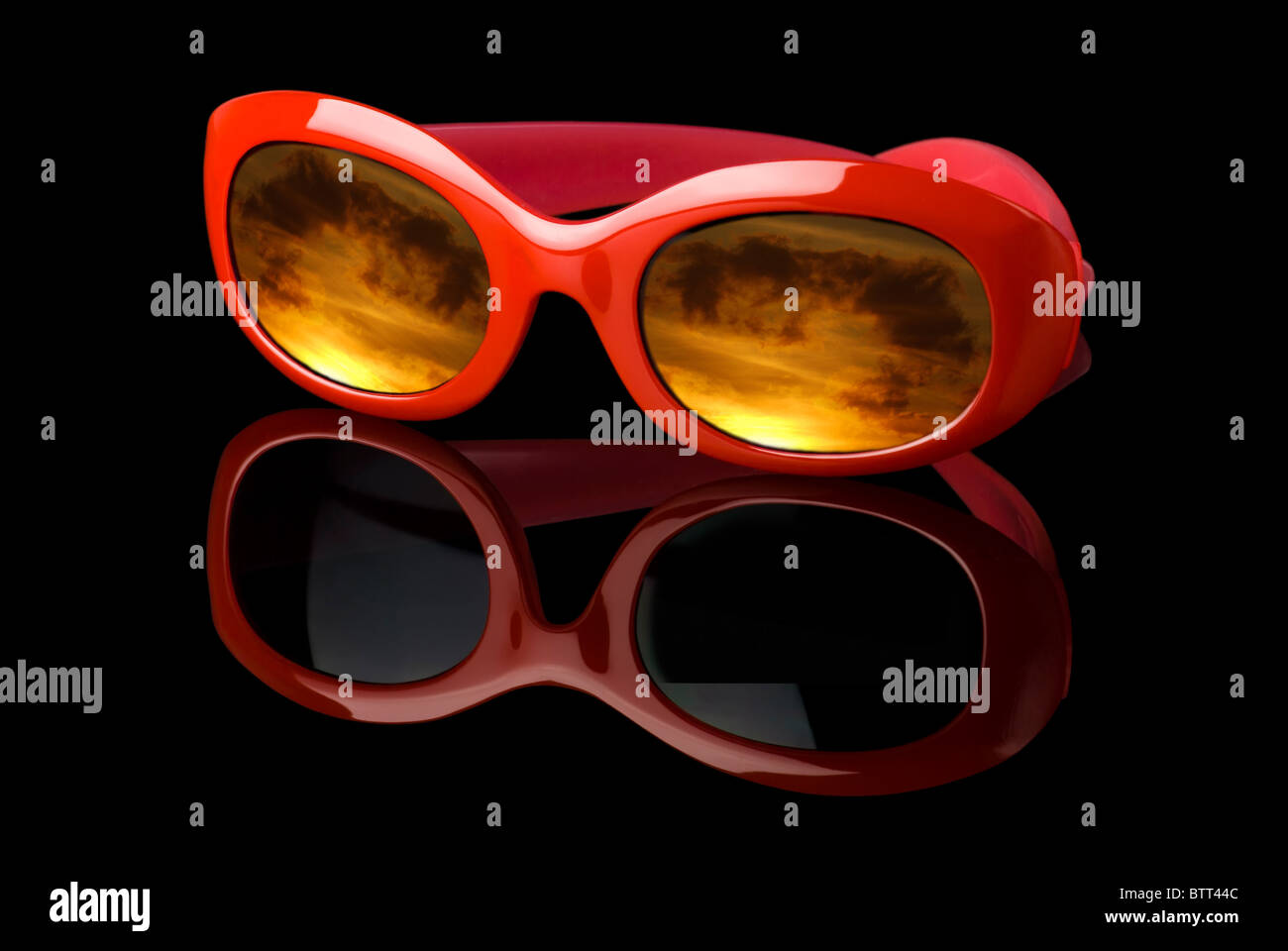 Futuristic sunglasses with sunset sky reflected over black surface with ...
