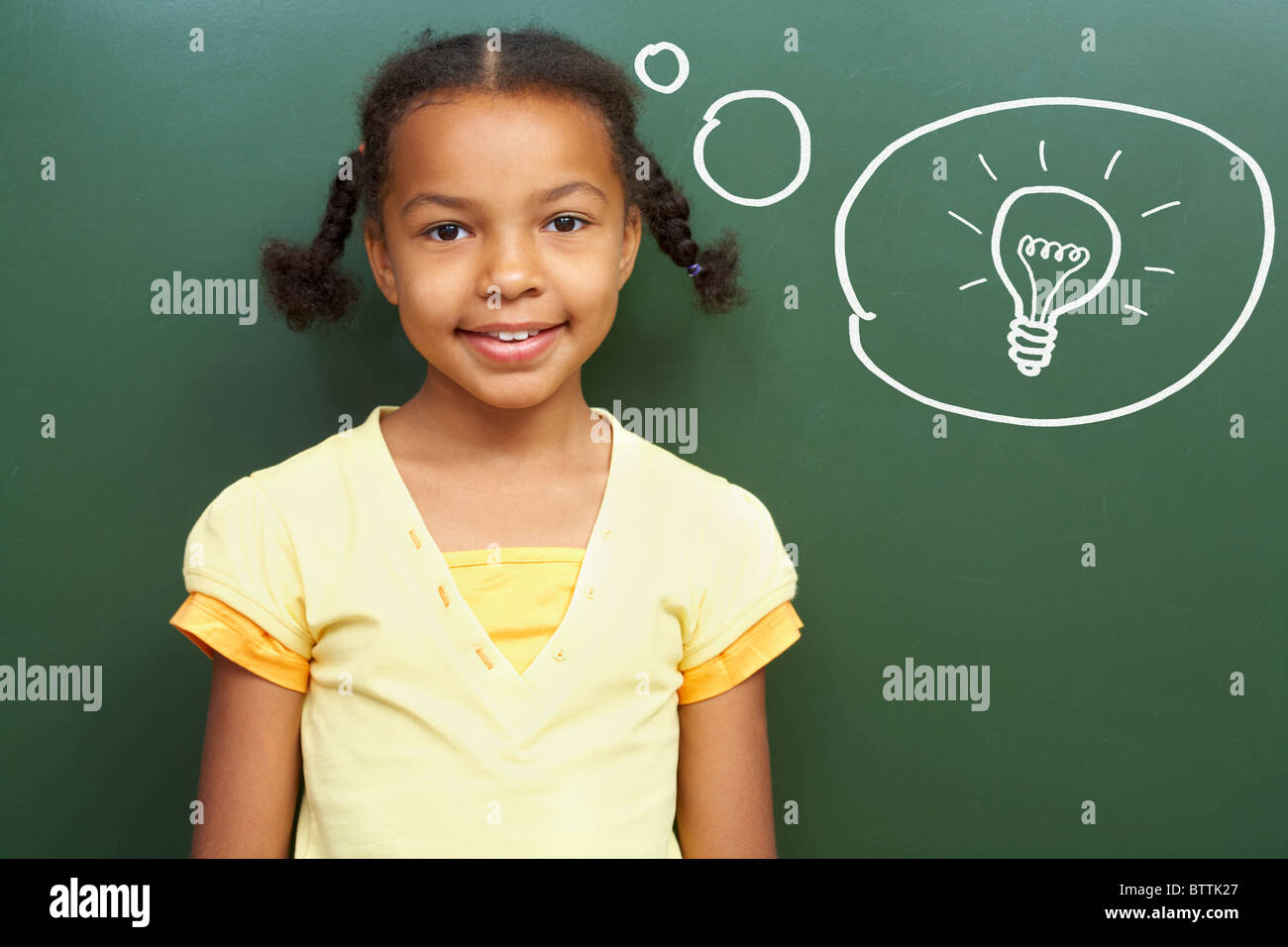 Portrait of smart girl by the blackboard thinking of light idea and ...
