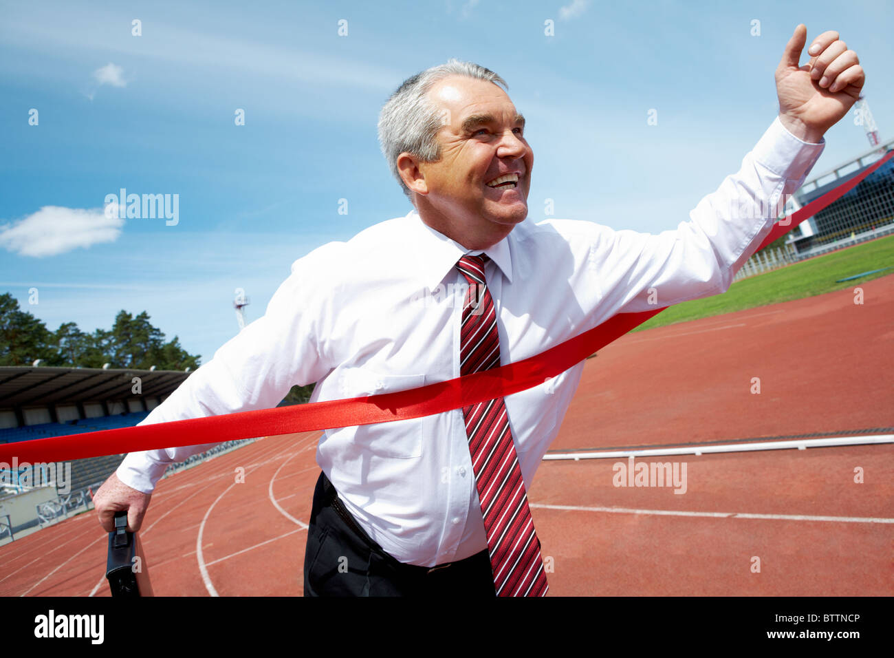 Photo of happy mature businessman crossing finish line during race ...