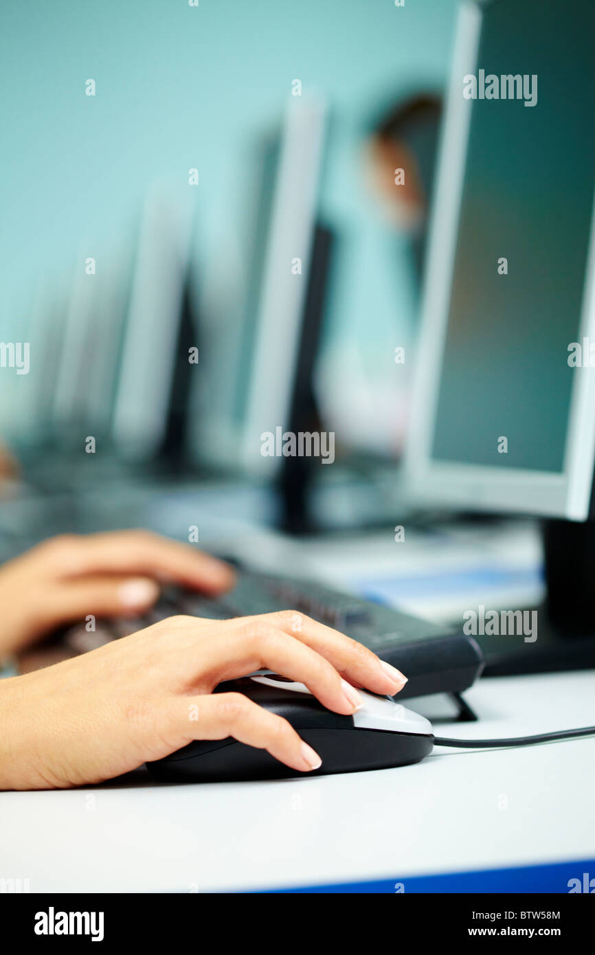 Image of female hand on mouse while typing on keyboard in a working ...