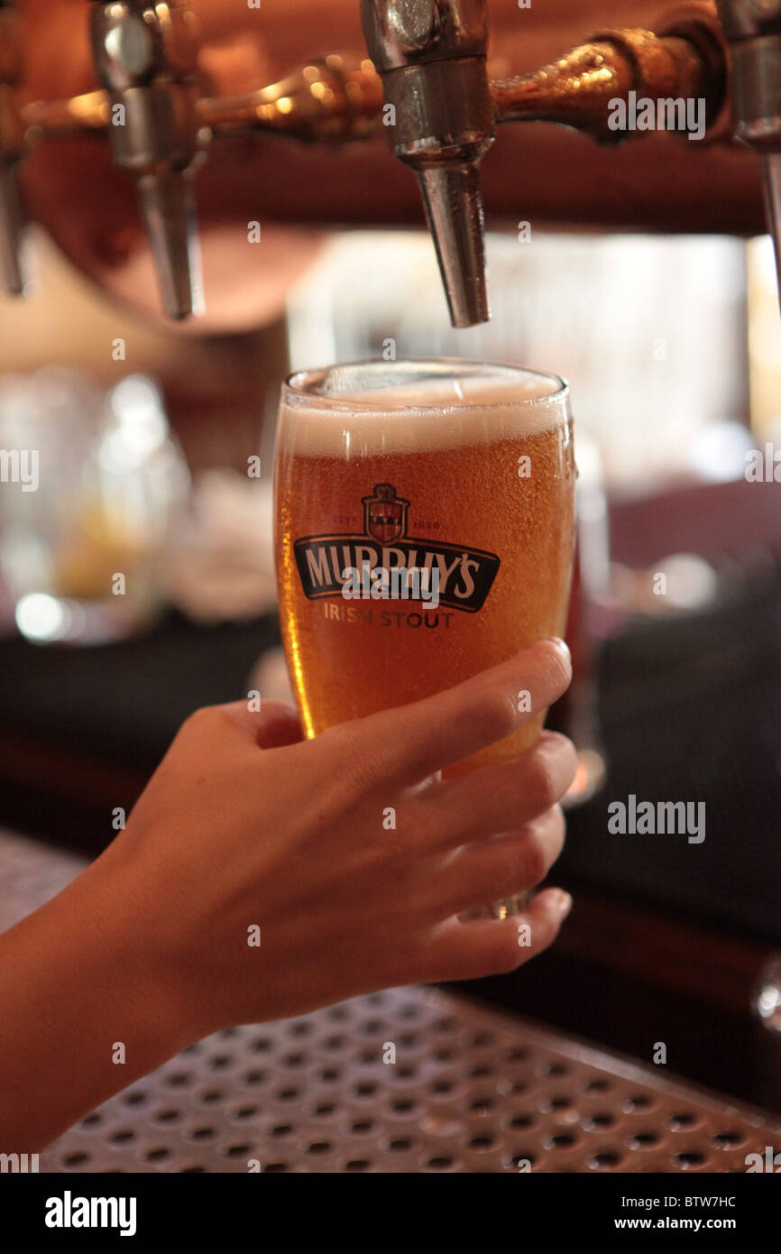 Interior of an Irish style pub draught beer taps. Barmaid pouring a ...
