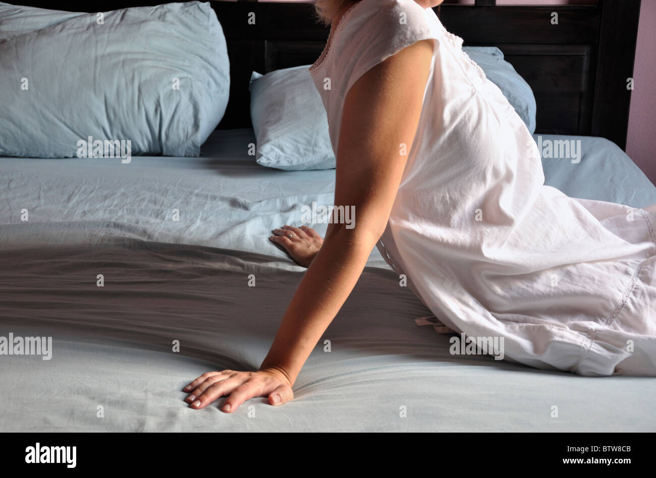 Young woman sitting on bed Stock Photo - Alamy