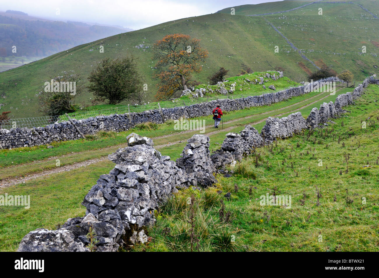 Rambler walking on a footpath above the village of Starbotton ...