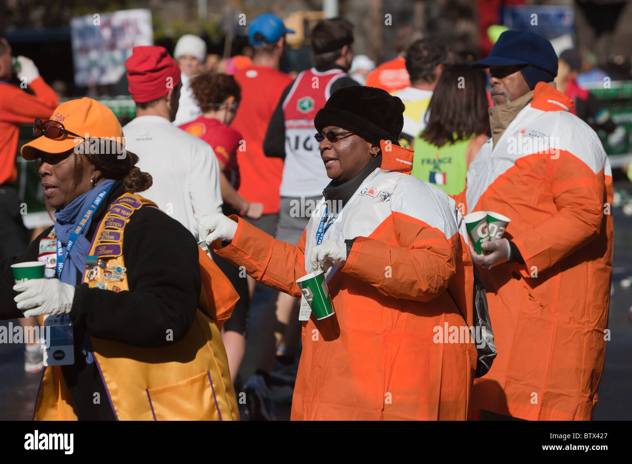 Volunteers at a fluid station hand out water and Gatorade to runners ...