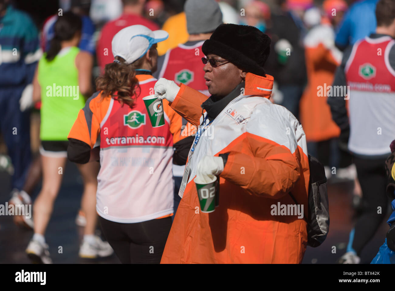 Volunteers at a fluid station hand out water and Gatorade to runners ...