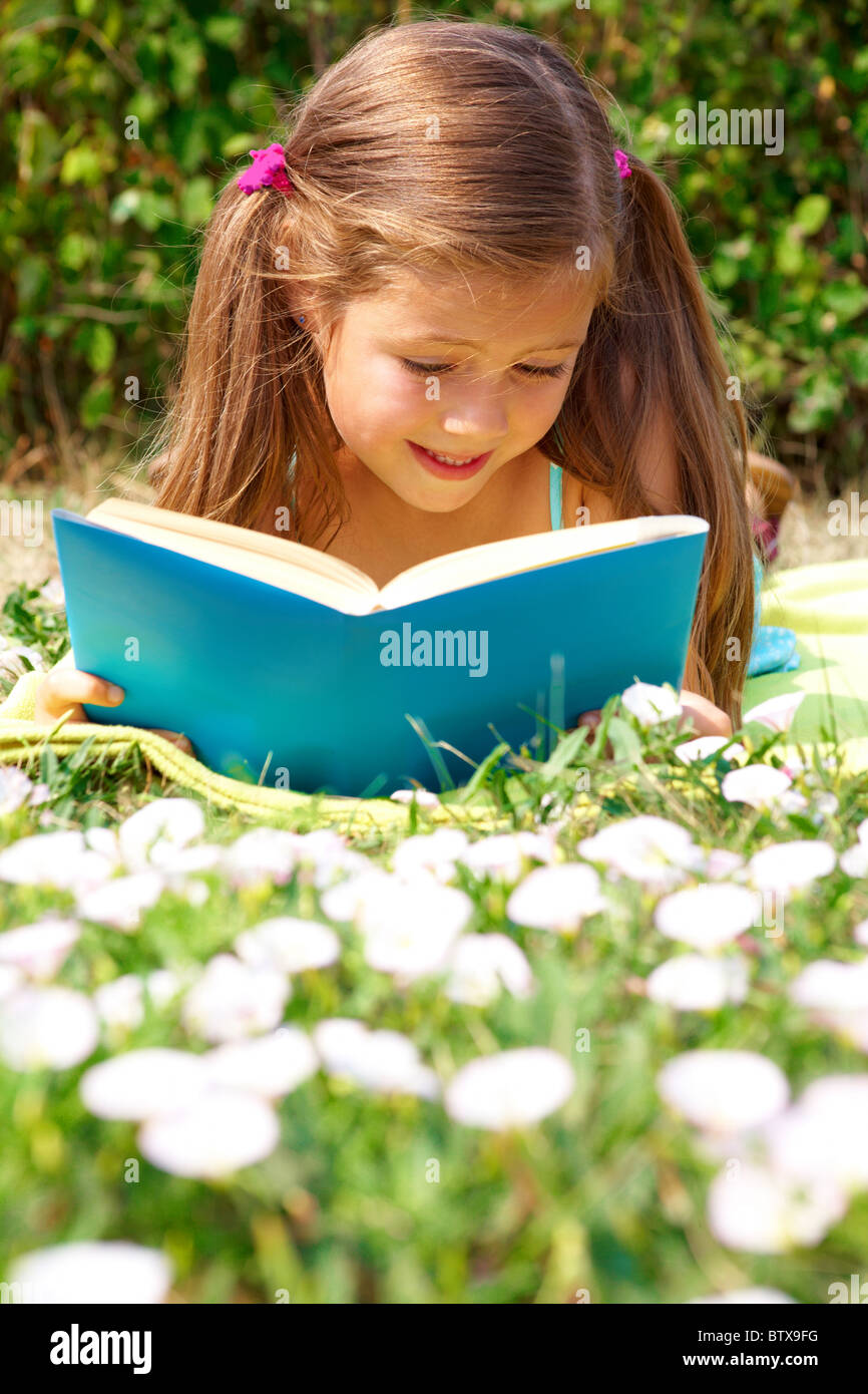 Portrait of cute schoolgirl reading interesting book in natural ...